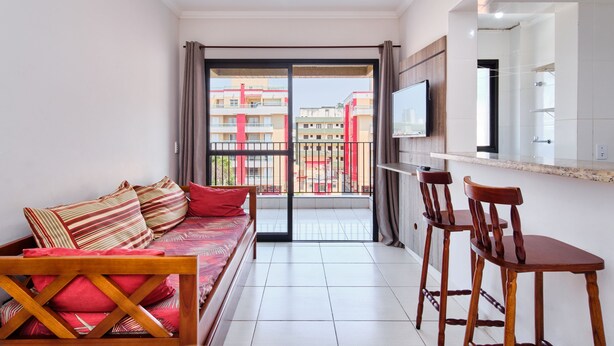 Quarto com cama, televisão, varanda e área de jantar.