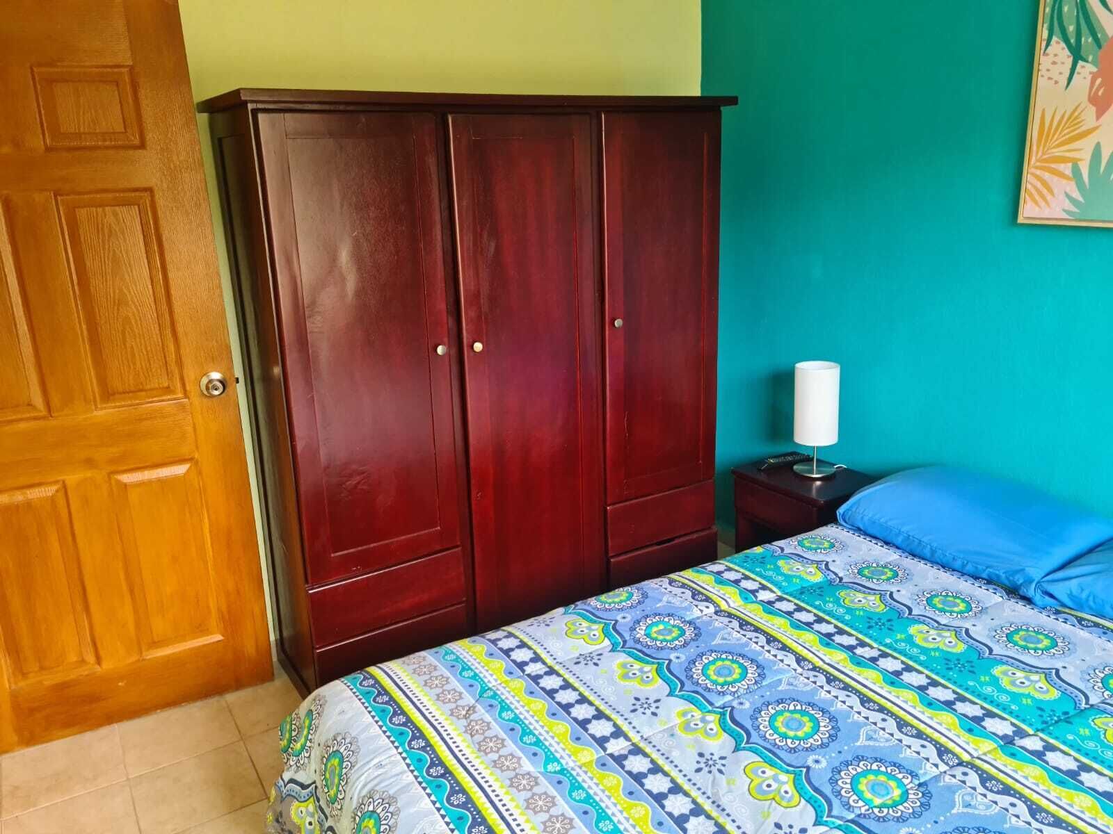 Um quarto com uma cama, um guarda-roupa e uma mesa de cabeceira.