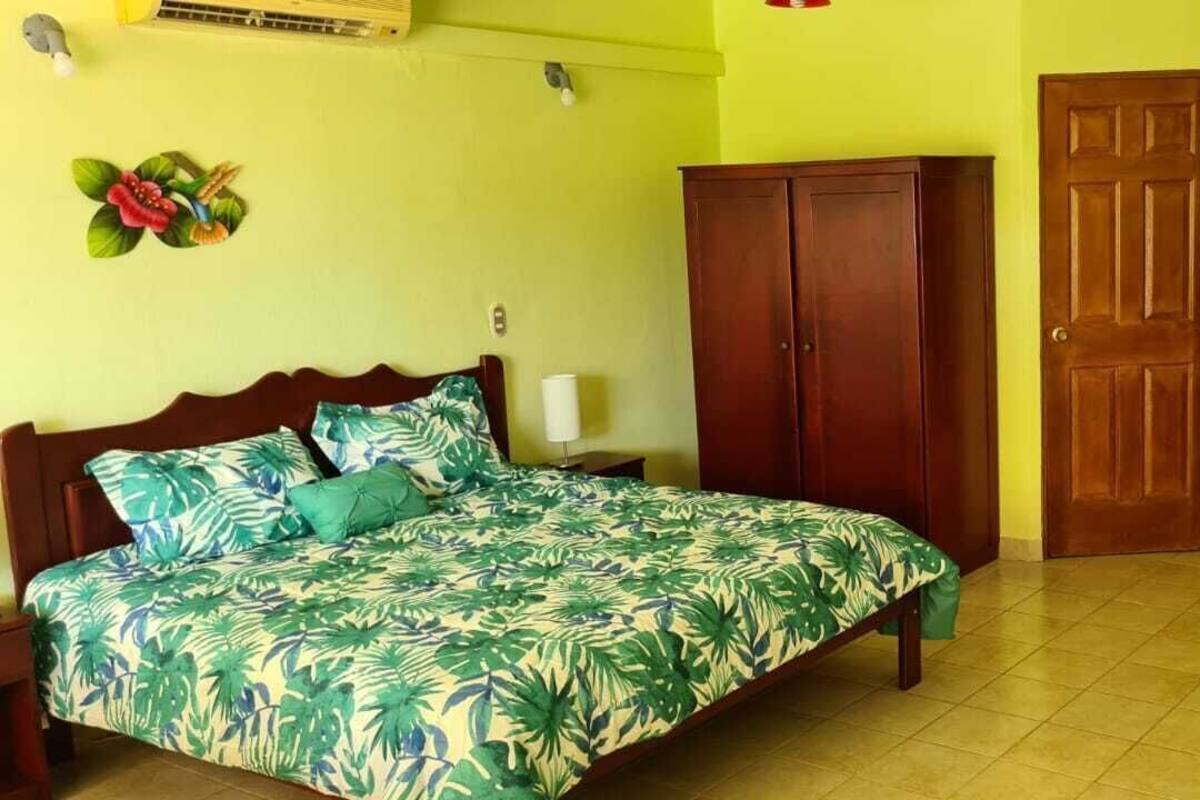 Quarto com cama, guarda-roupa e um pequeno espaço de refeições com mesa e cadeiras.