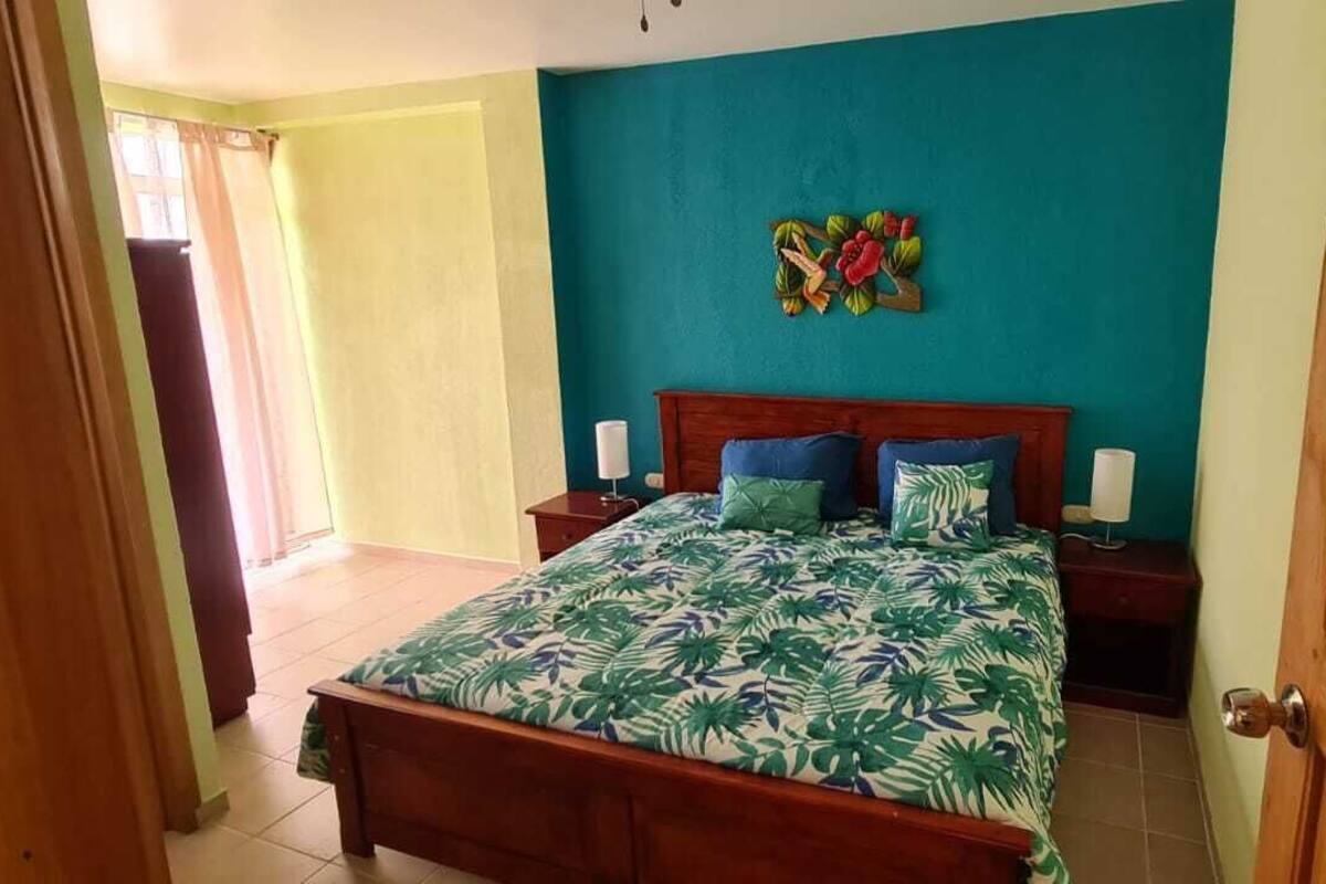 Quarto com cama, mesas de cabeceira e uma porta.