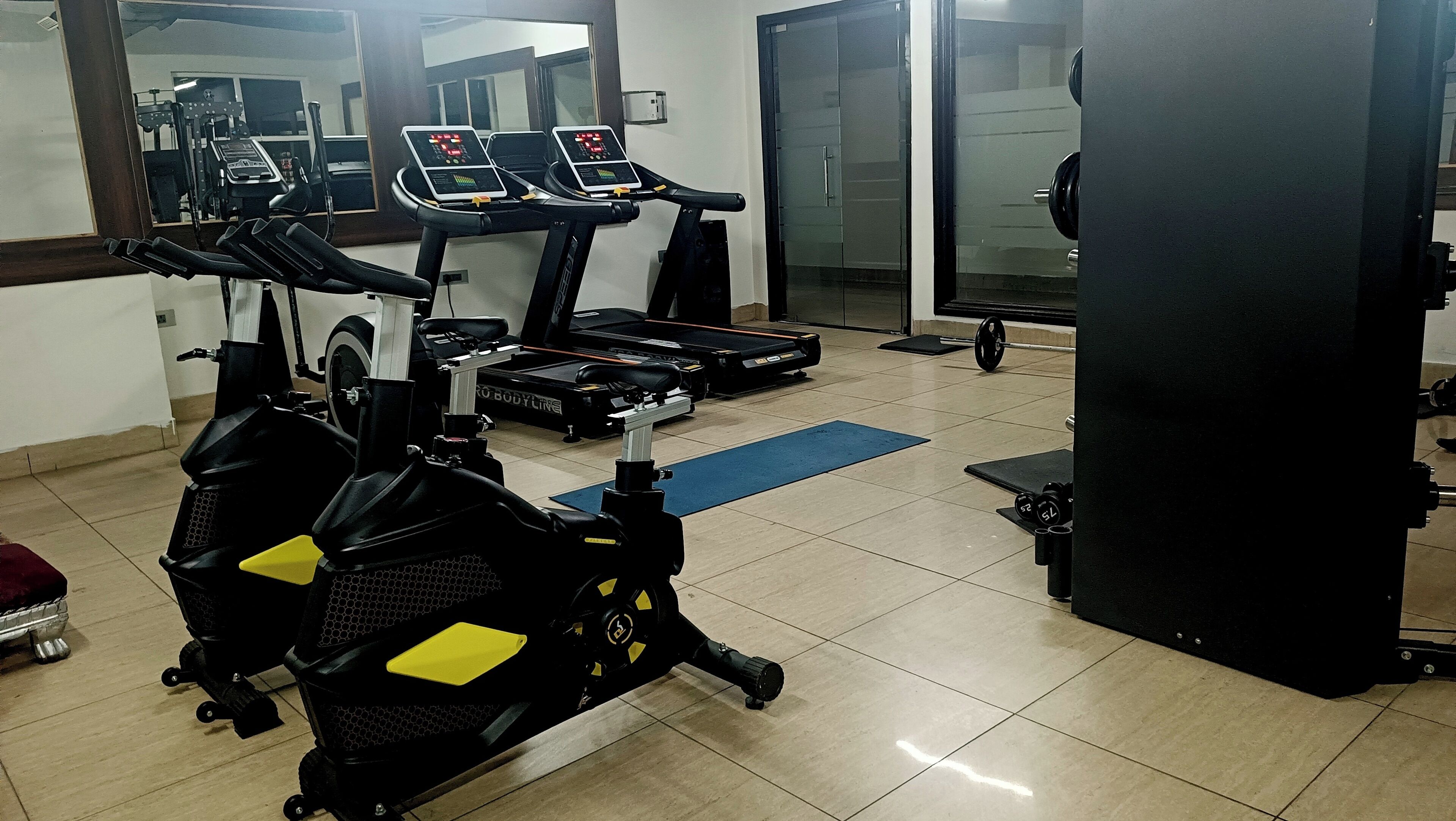 Academia com esteiras, bicicleta ergométrica e equipamentos de musculação.