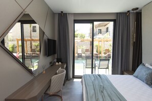 Quarto de hotel moderno com uma cama grande, uma escrivaninha, uma cadeira, uma TV e vista para uma piscina e área de estar ao ar livre.