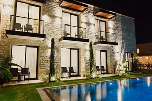 Um edifício moderno com piscina, grandes janelas e áreas de estar ao ar livre.