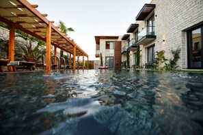 Um hotel moderno com piscina, área de estar externa e uma parede de pedra.