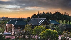 Um edifício moderno com telhado verde, cercado por árvores e um céu claro.