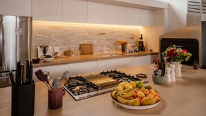 Cozinha moderna com fogão a gás, pia e bancada com frutas e utensílios.