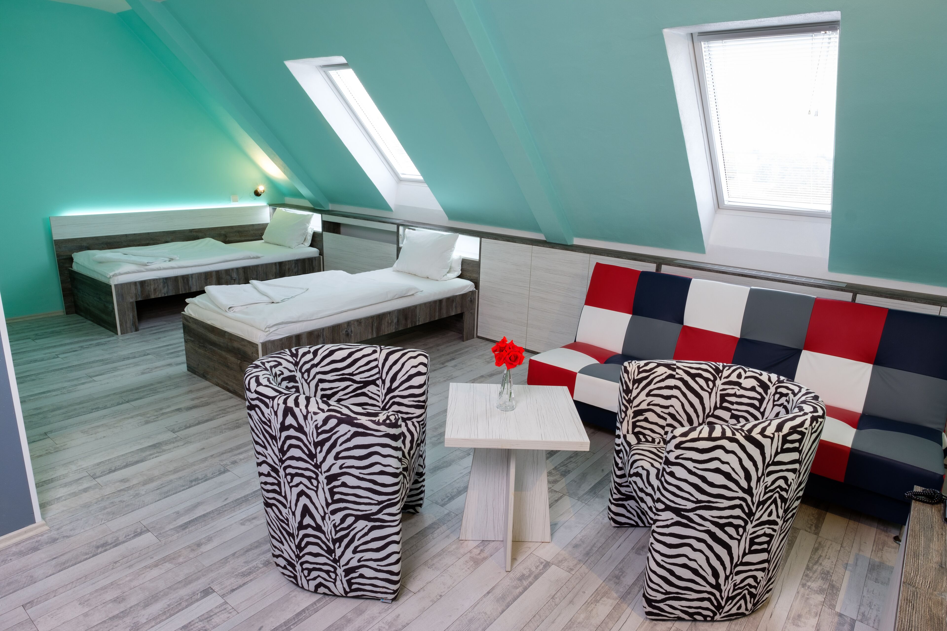 Quarto moderno estilo loft com teto inclinado, cama, sofá e uma mesinha.