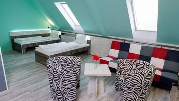 Quarto moderno estilo loft com teto inclinado, cama, sofá e uma mesinha.