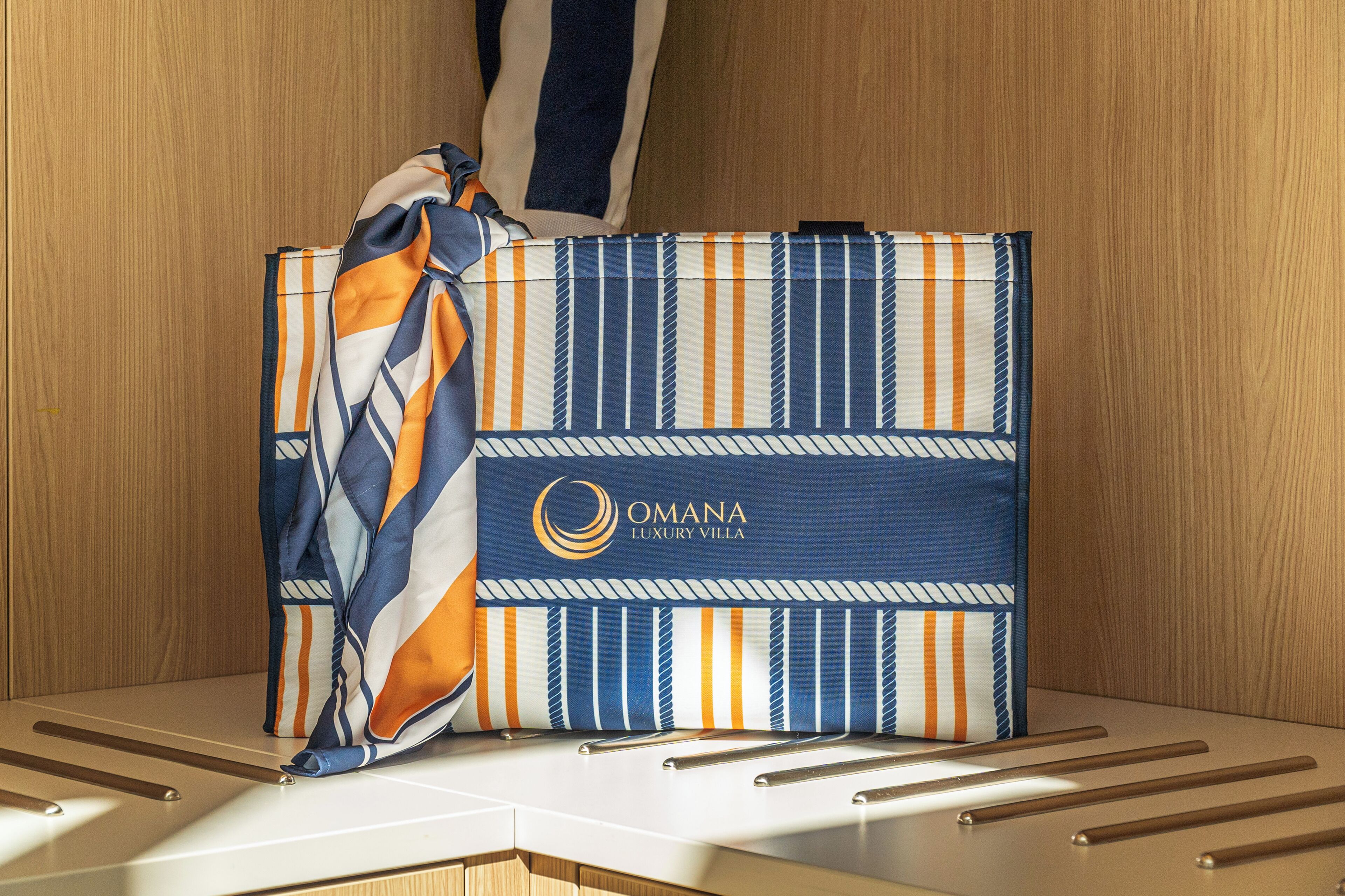 Uma bolsa estampada com a inscrição 'OMANA LUXURY VILLA' sobre uma superfície de madeira.