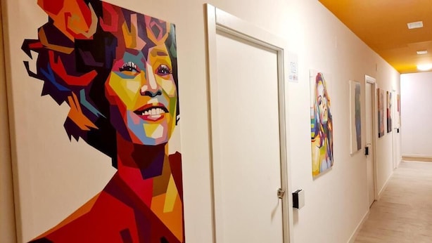 Um corredor com várias portas, cada uma com uma pintura colorida na parede.