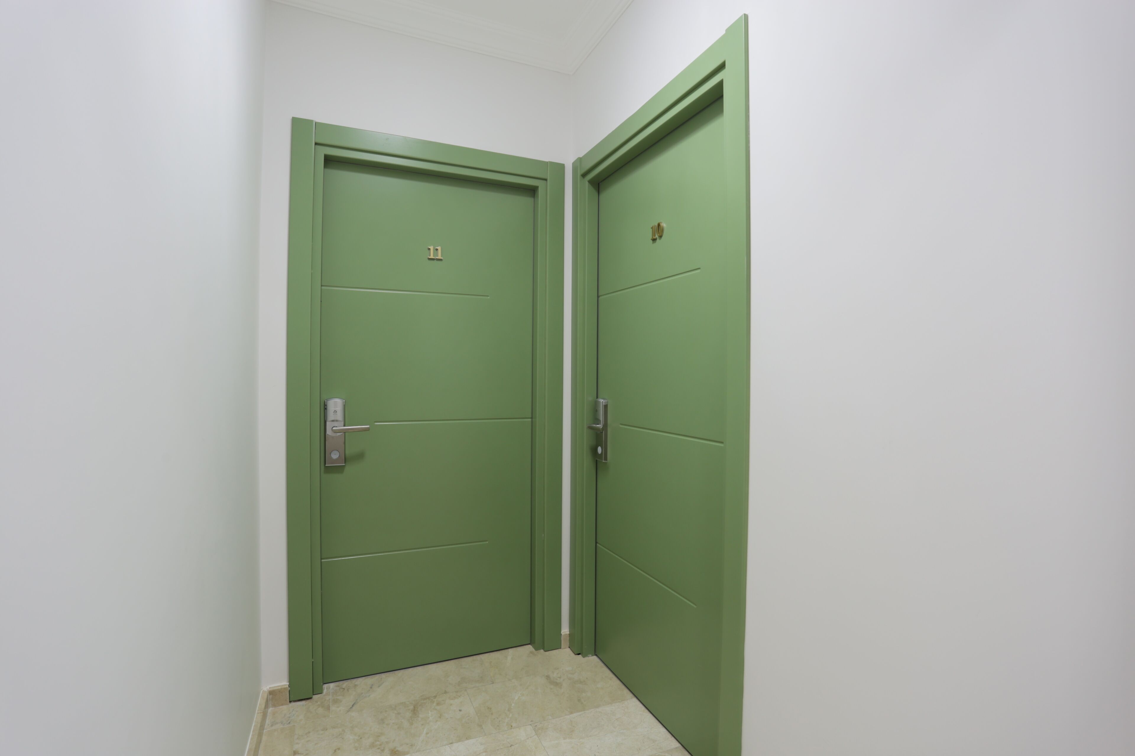 Uma porta verde com teclado numérico, um interfone e uma pequena placa de latão com o número 11.