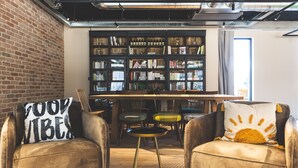 Um espaço acolhedor para leitura, com poltronas de couro, uma estante de livros e uma mesa de madeira.