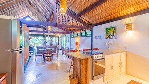 Cozinha com fogão a gás, geladeira e área de refeições com cadeiras e mesa.
