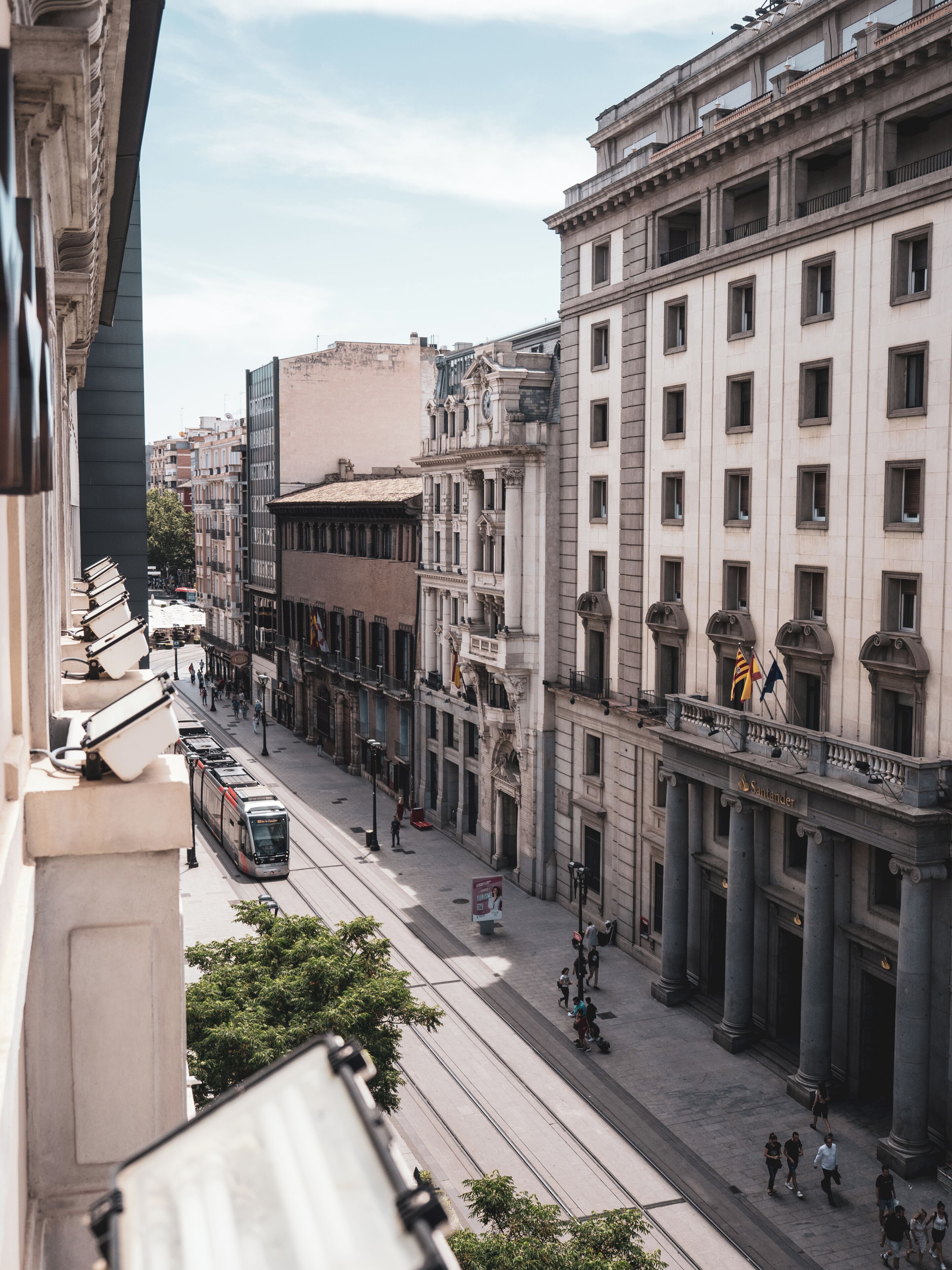 Vista da rua com bonde, edifícios históricos e pedestres.