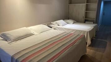 Quarto de hotel com duas camas de solteiro, um guarda-roupa e ar condicionado instalado.