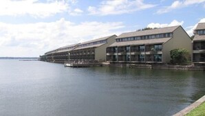 Um hotel na orla marítima, com vários edifícios, um cais e uma superfície aquática calma.