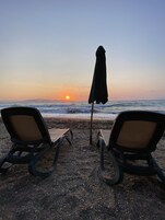Praia particular, areia preta, espreguiçadeiras, guarda-sóis 