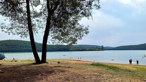 Vista para o lago com área de piquenique, árvores e pessoas perto da água.
