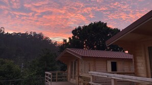 Uma cabana de madeira com telhado de telhas, um deck de madeira e um caminho de pedra que leva à entrada.