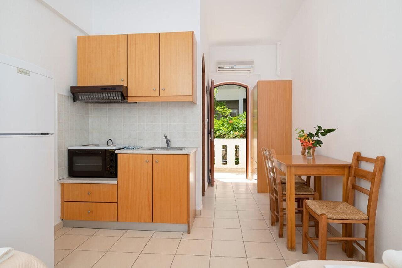 Uma cozinha compacta com armários de madeira, micro-ondas e área de jantar com mesa e cadeiras.