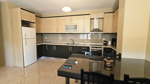 Cozinha moderna com ilha central, eletrodomésticos de aço inoxidável e armários em madeira clara.