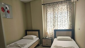 Quarto duplo com duas camas, uma mesa de cabeceira com abajur e um quadro na parede.