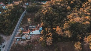 Vista aérea de uma área costeira com praia, floresta densa e alguns edifícios.