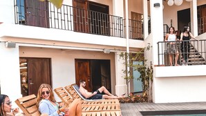 Área da piscina com espreguiçadeiras de madeira, piscina e um edifício com varandas e uma placa com a inscrição 'ONDA'.