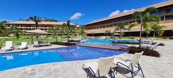 Um hotel com uma grande piscina ao ar livre, espreguiçadeiras e palmeiras.