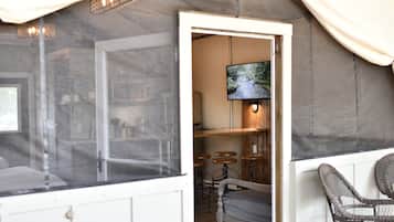 Quarto com uma cama, uma televisão na parede e um espaço de bar com bancos.