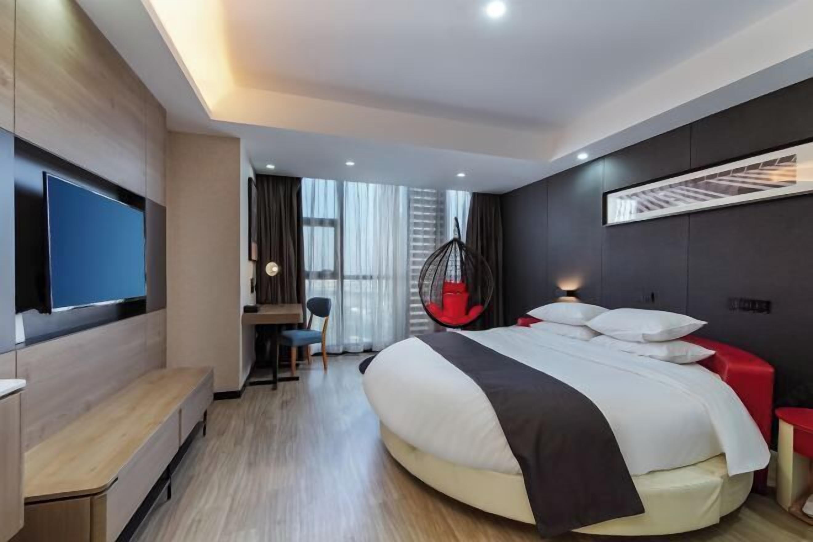 Quarto de hotel moderno com uma cama grande, uma mesa e uma televisão.