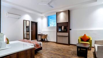 Quarto de hotel moderno com cama, escrivaninha, cadeira, televisão e janela com vista.