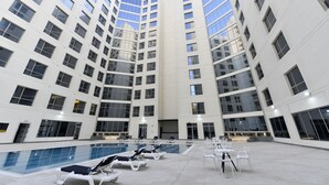 Interior moderno de hotel com piscina central, vários andares e teto alto.
