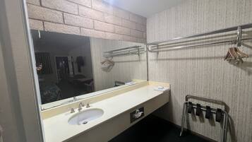 Casa de banho com um espelho grande, lavatório e um porta-toalhas.