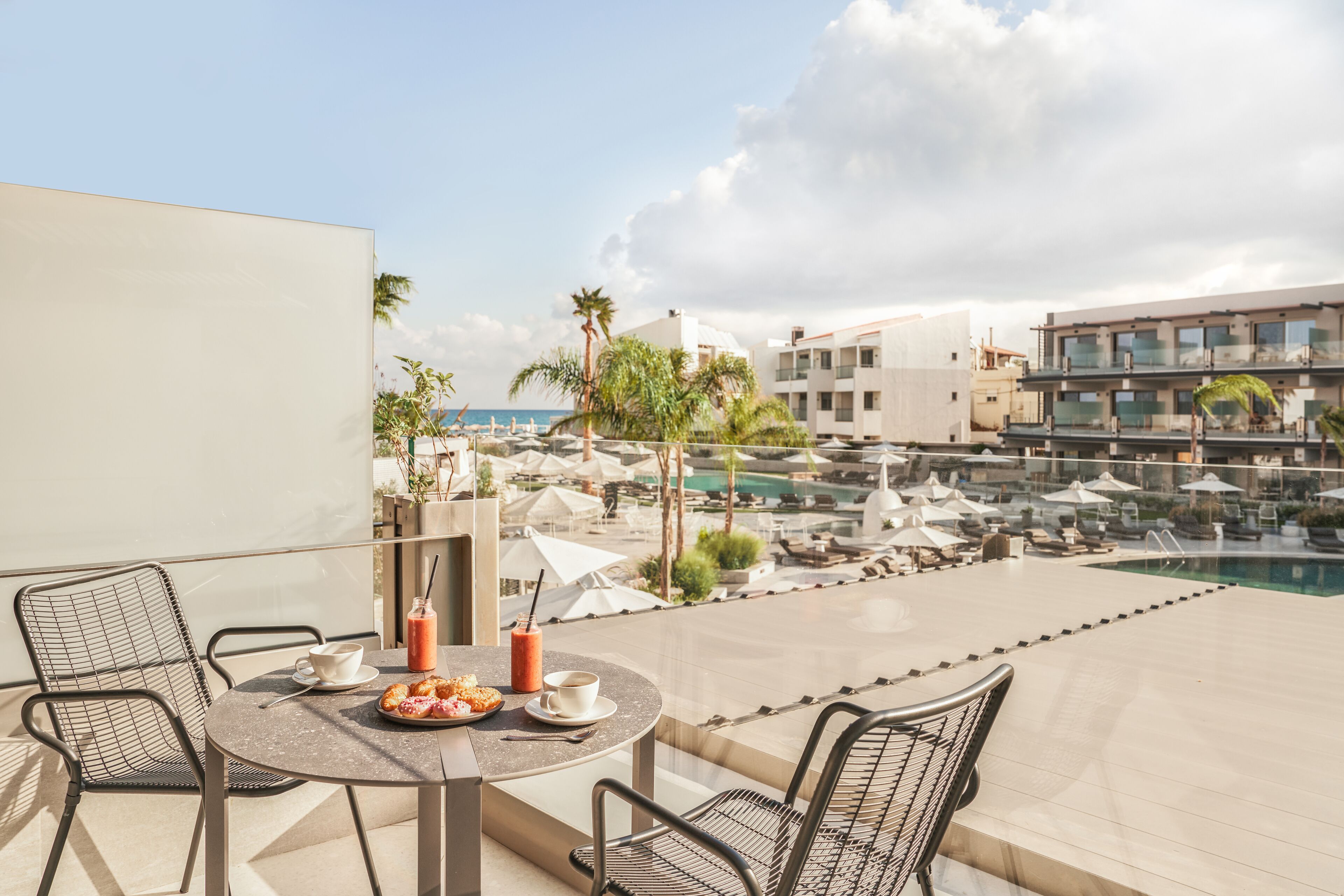Terraço no telhado com mesa posta para dois, com vista para uma área de piscina e uma praia.