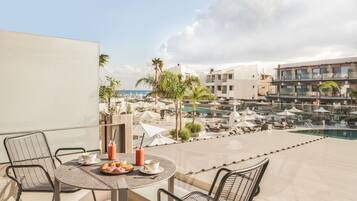 Terraço no telhado com mesa posta para dois, com vista para uma área de piscina e uma praia.