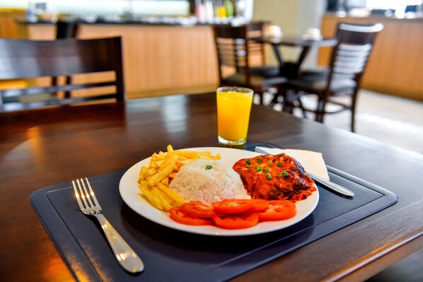 Uma mesa de jantar com um prato de comida, um copo de suco de laranja e talheres.