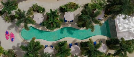 Vista aérea de um resort com piscina, espreguiçadeiras e palmeiras.
