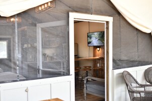 Quarto com uma cama, uma televisão na parede e um espaço de bar com bancos.