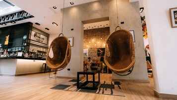 Um interior moderno com cadeiras de vime suspensas, um espaço de bar e uma parede de tijolos.