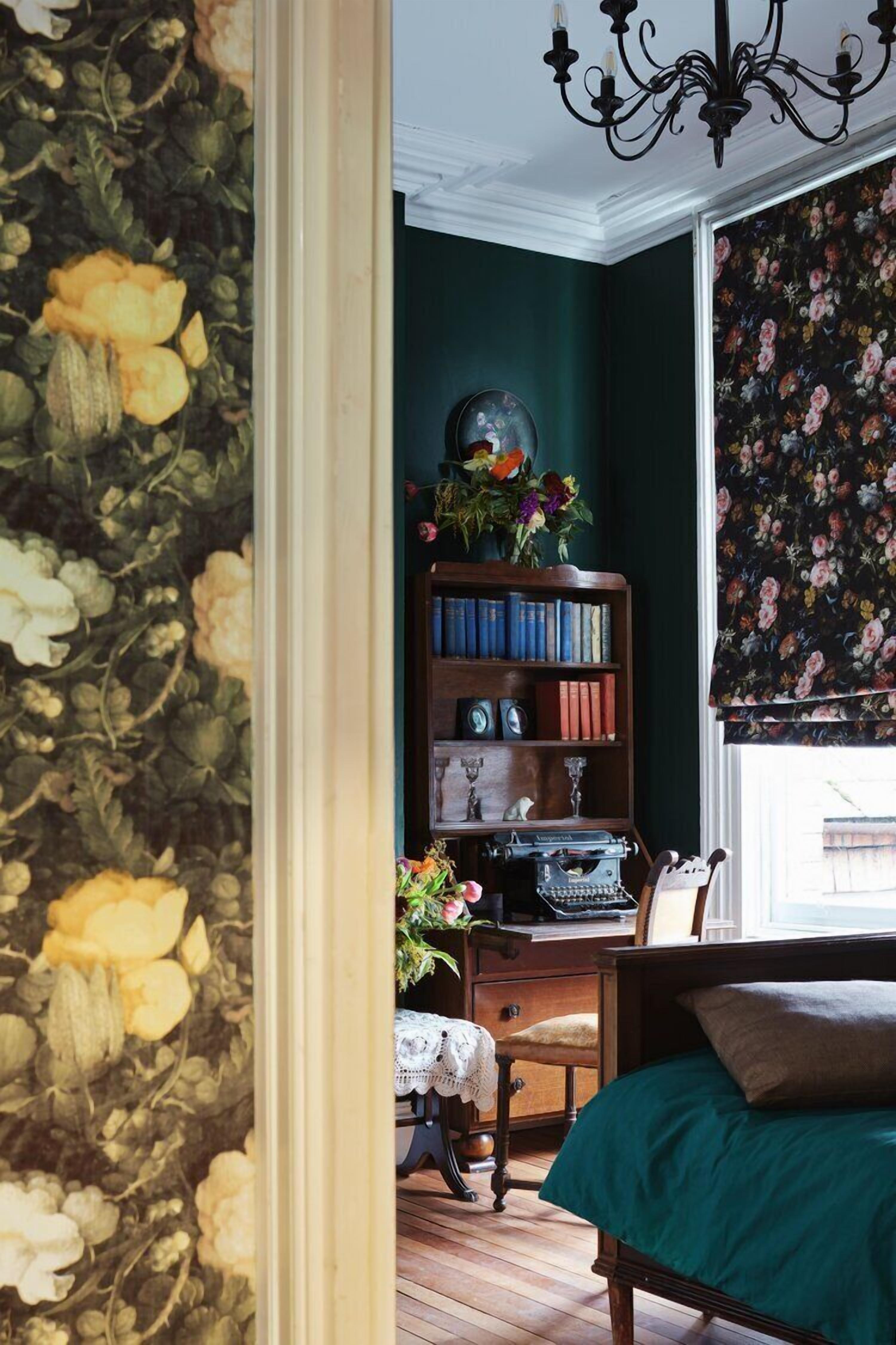 Quarto com cama verde, estante de madeira e máquina de escrever antiga.