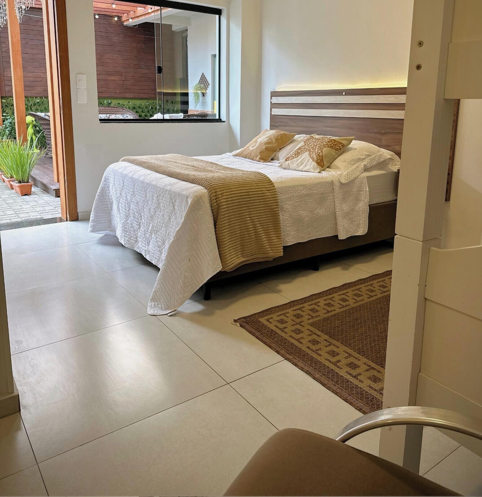 Quarto moderno com cama, mesa de cabeceira e vista para o exterior.