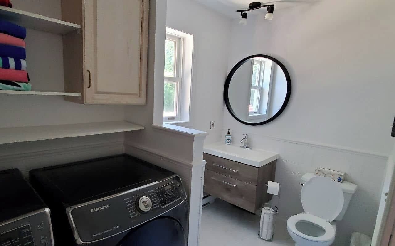 Uma casa de banho compacta com máquina de lavar roupa, lavatório e sanita.