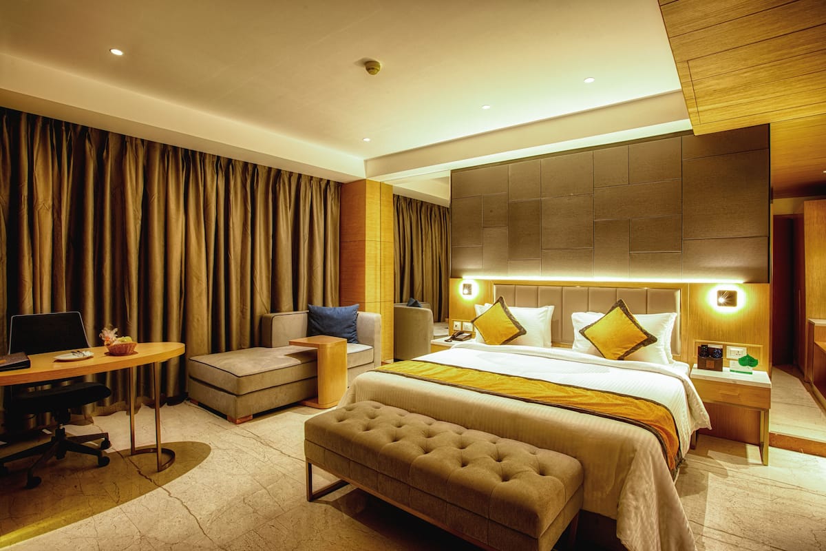 Quarto de hotel moderno com uma cama grande, uma escrivaninha, uma cadeira e um sofá.
