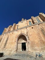 Um edifício histórico com uma grande entrada em arco, paredes de pedra e uma torre do relógio.