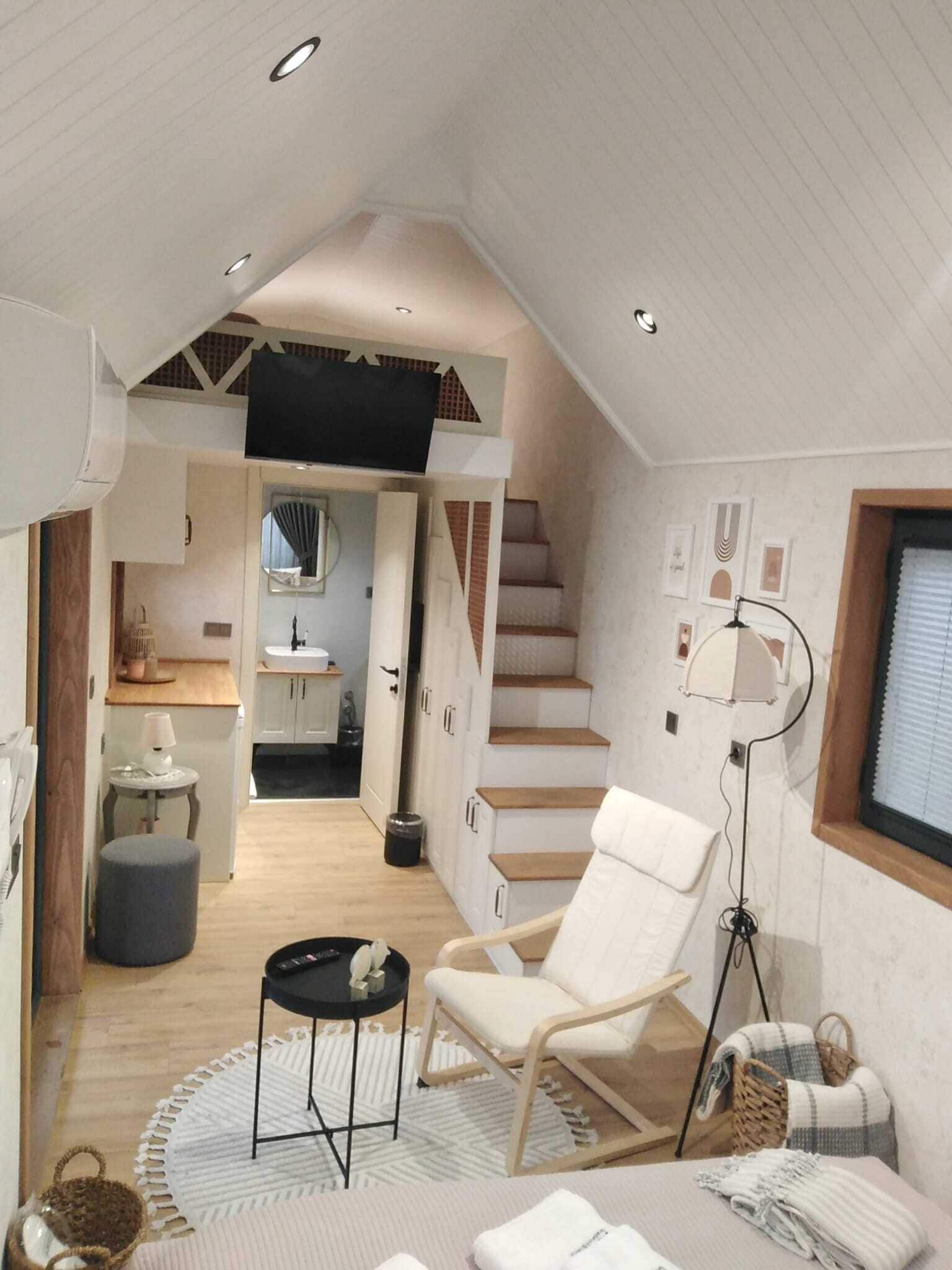Espaço de estar compacto e moderno, com quarto em mezzanine, área de refeições e cozinha.
