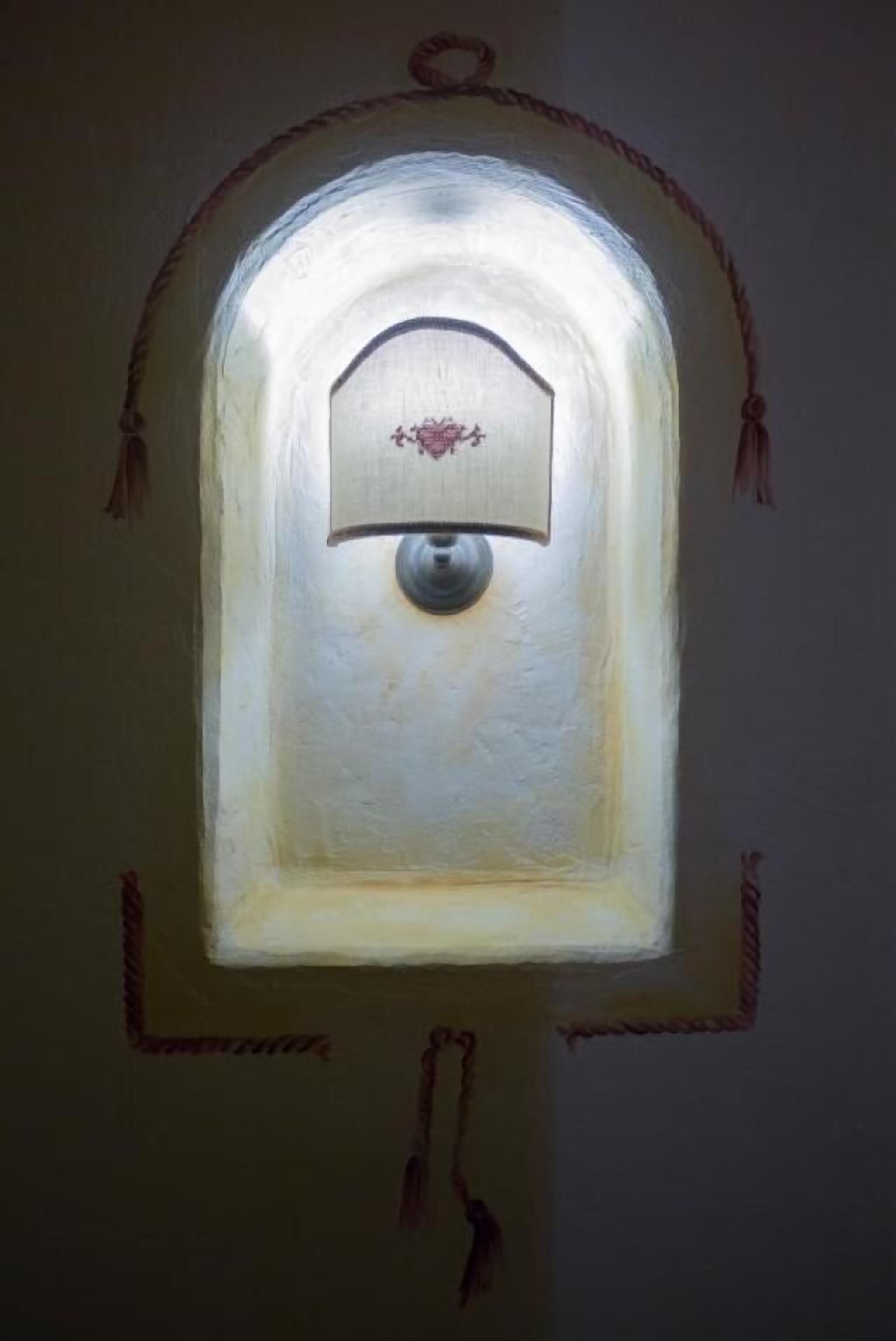 Luminária de parede com design decorativo e uma fonte de luz central.