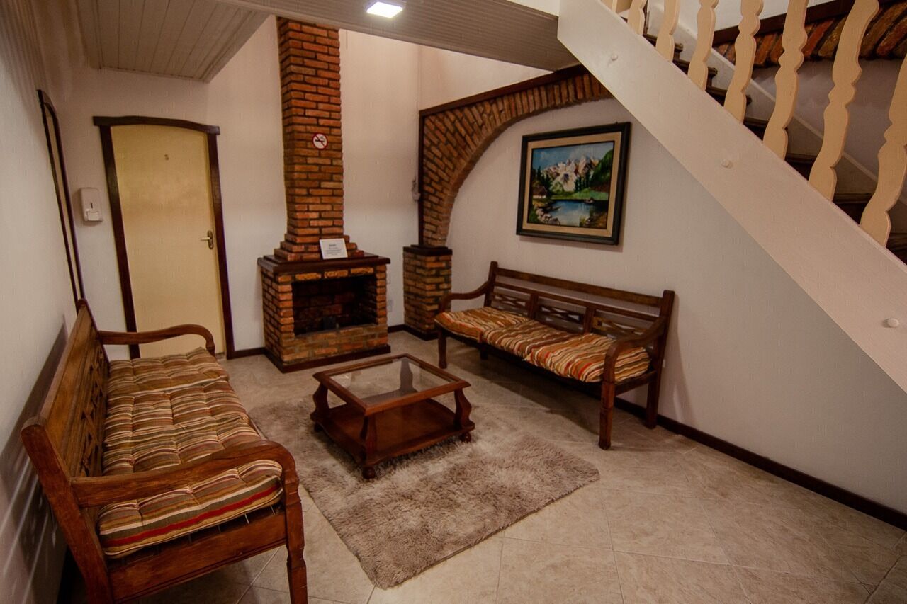 Sala de estar com lareira, móveis de madeira e escada.