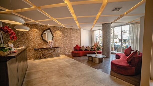 Um lobby moderno com parede de pedra, sofás vermelhos, mesa de centro redonda e um espelho grande.