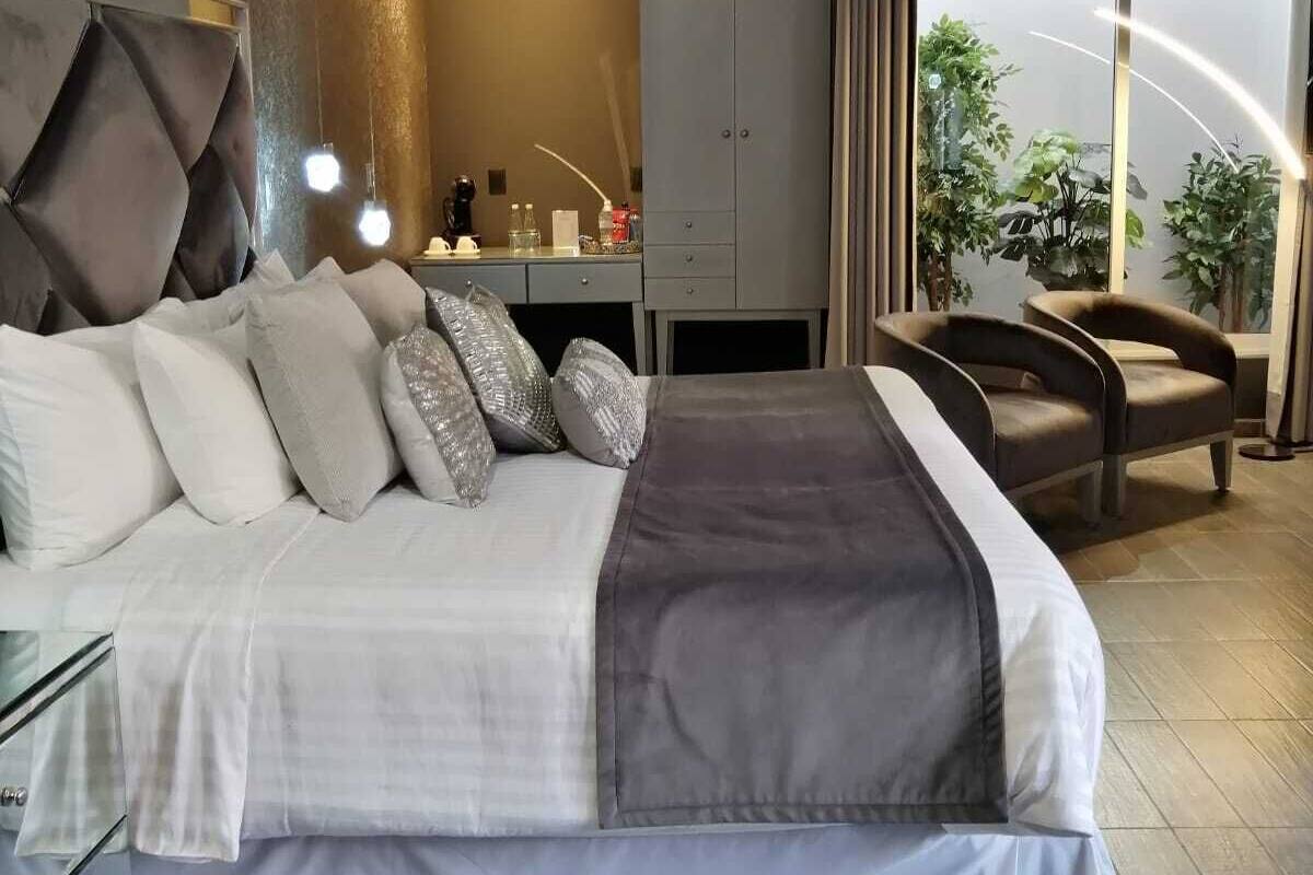 Quarto de hotel moderno com uma cama grande, uma escrivaninha e vista para o exterior.